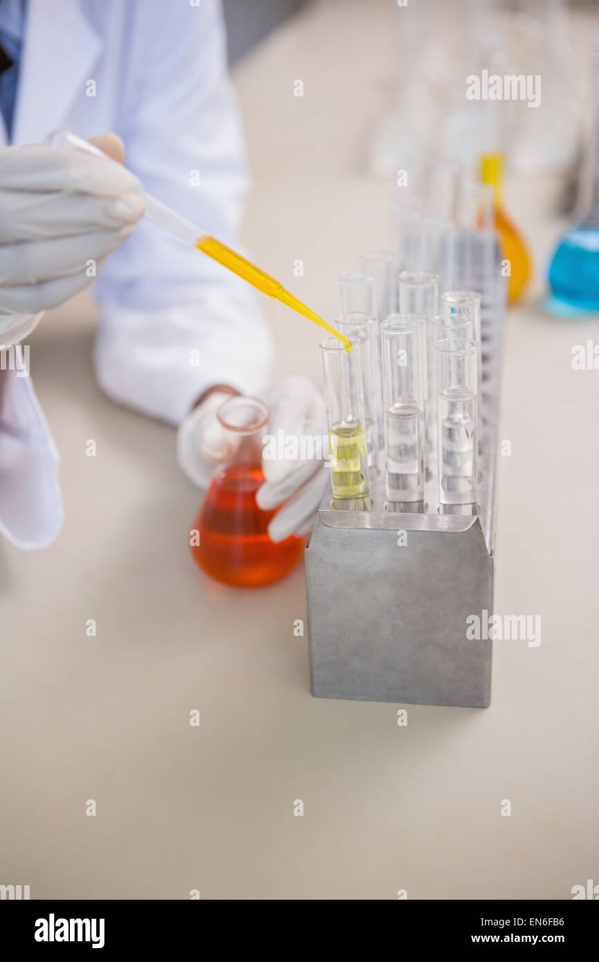 Scientist pouring orange fluid in test tube Stock Photo - Alamy