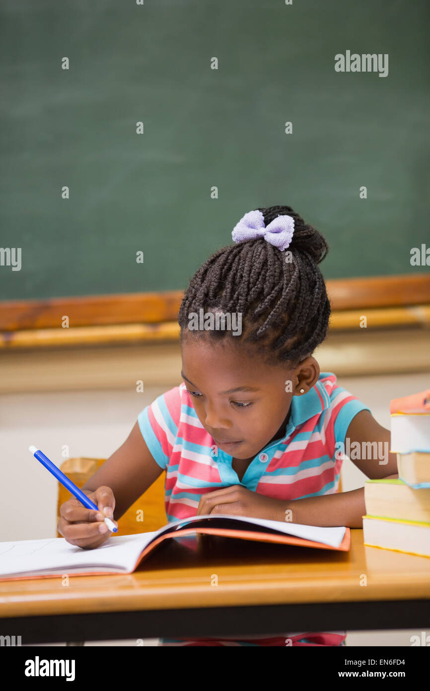 Cute pupils writing at desk in classroom Stock Photo - Alamy