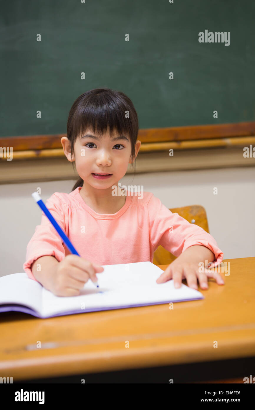 Cute pupil writing at desk in classroom Stock Photo - Alamy