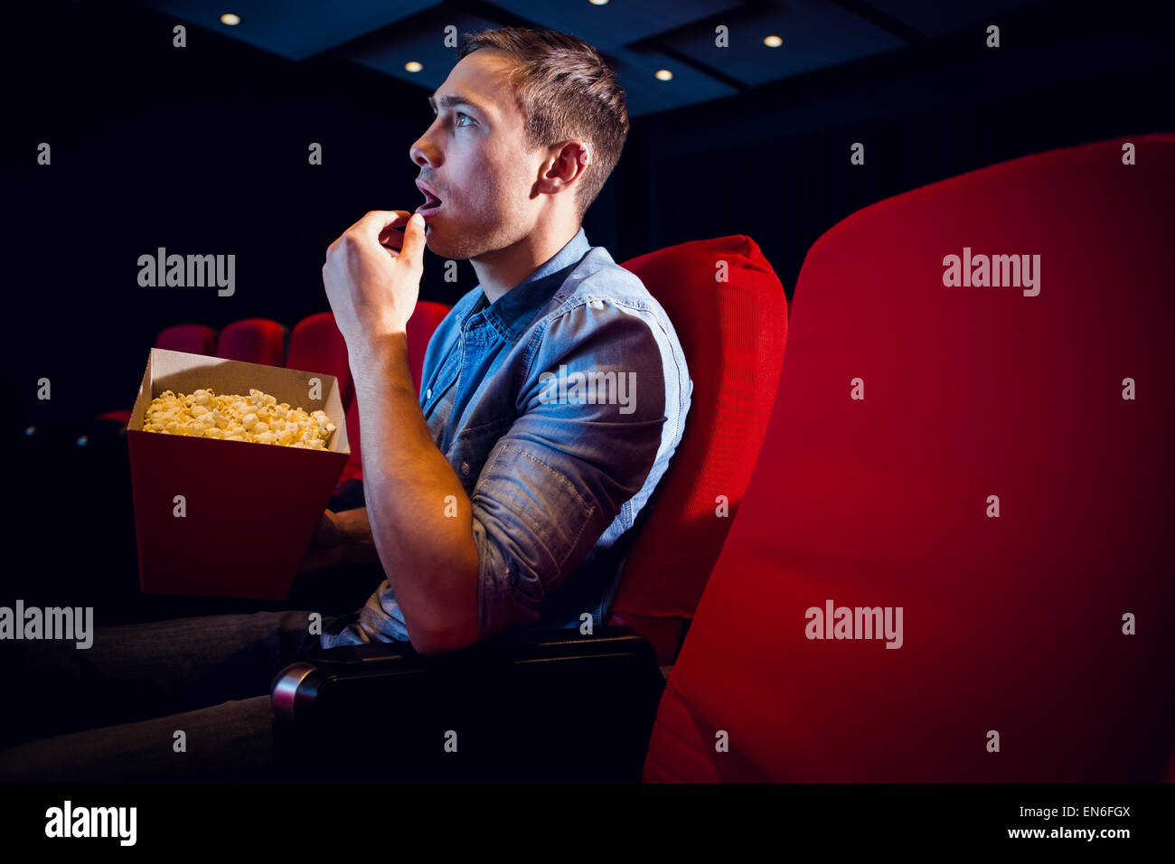 Young man watching a film Stock Photo - Alamy