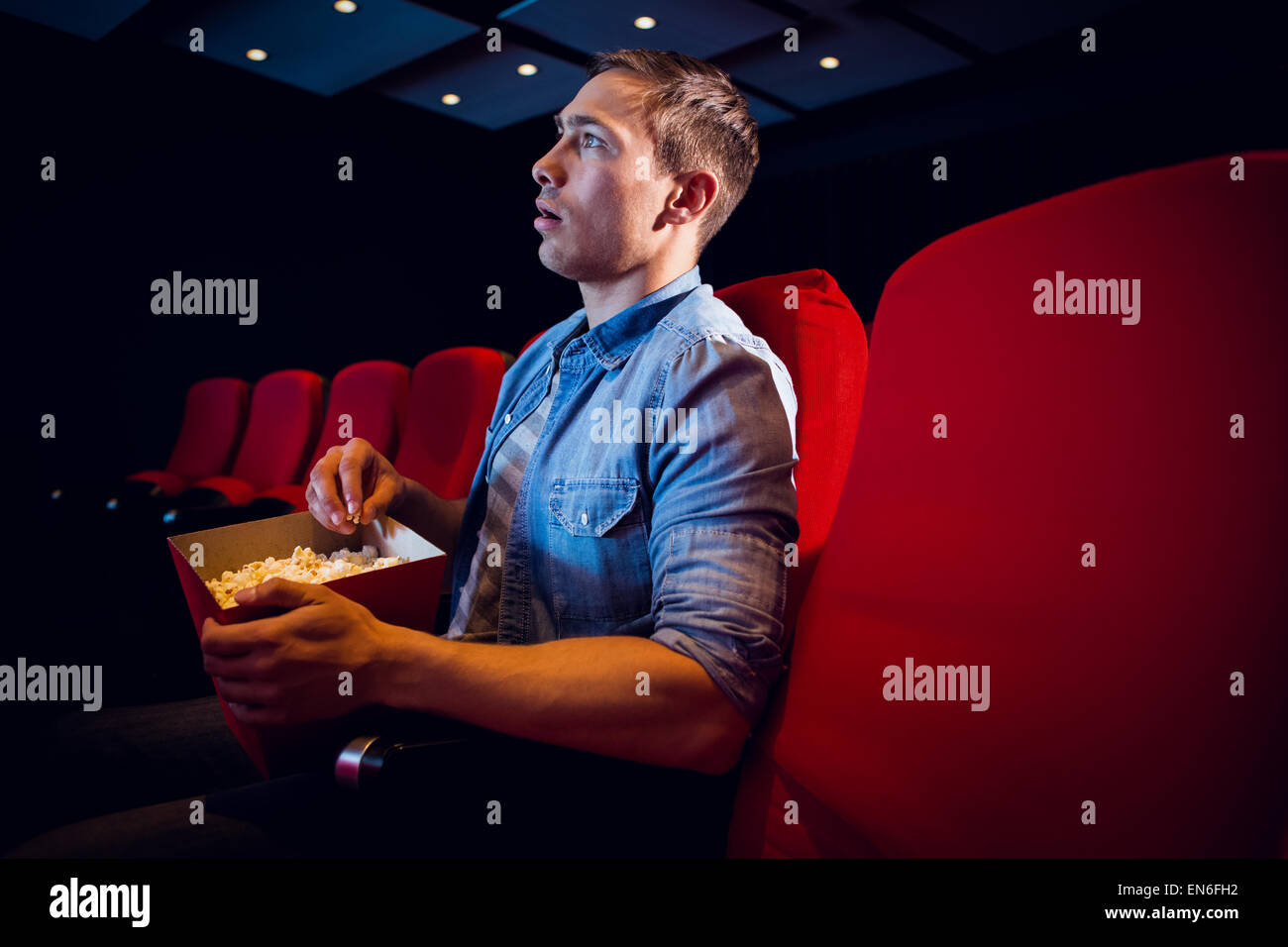 Young man watching a film Stock Photo - Alamy