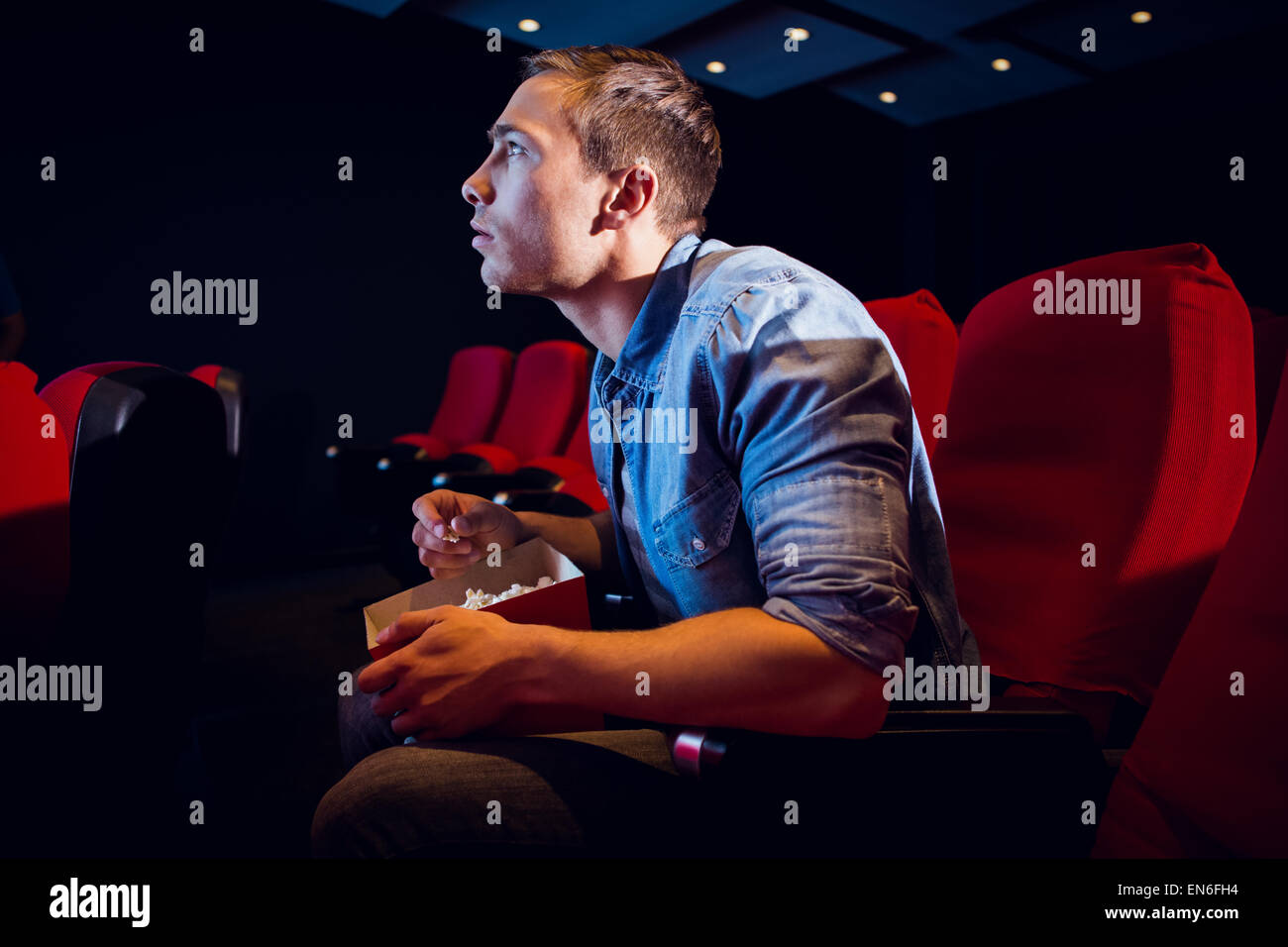 Young man watching a film Stock Photo - Alamy