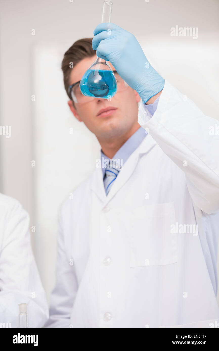 Scientist looking at beaker with blue fluid Stock Photo - Alamy