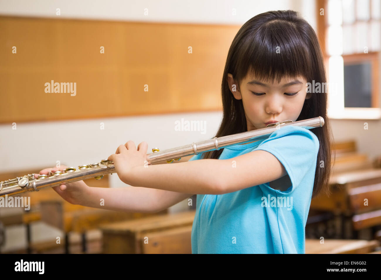 Cute pupil playing flute in classroom Stock Photo - Alamy