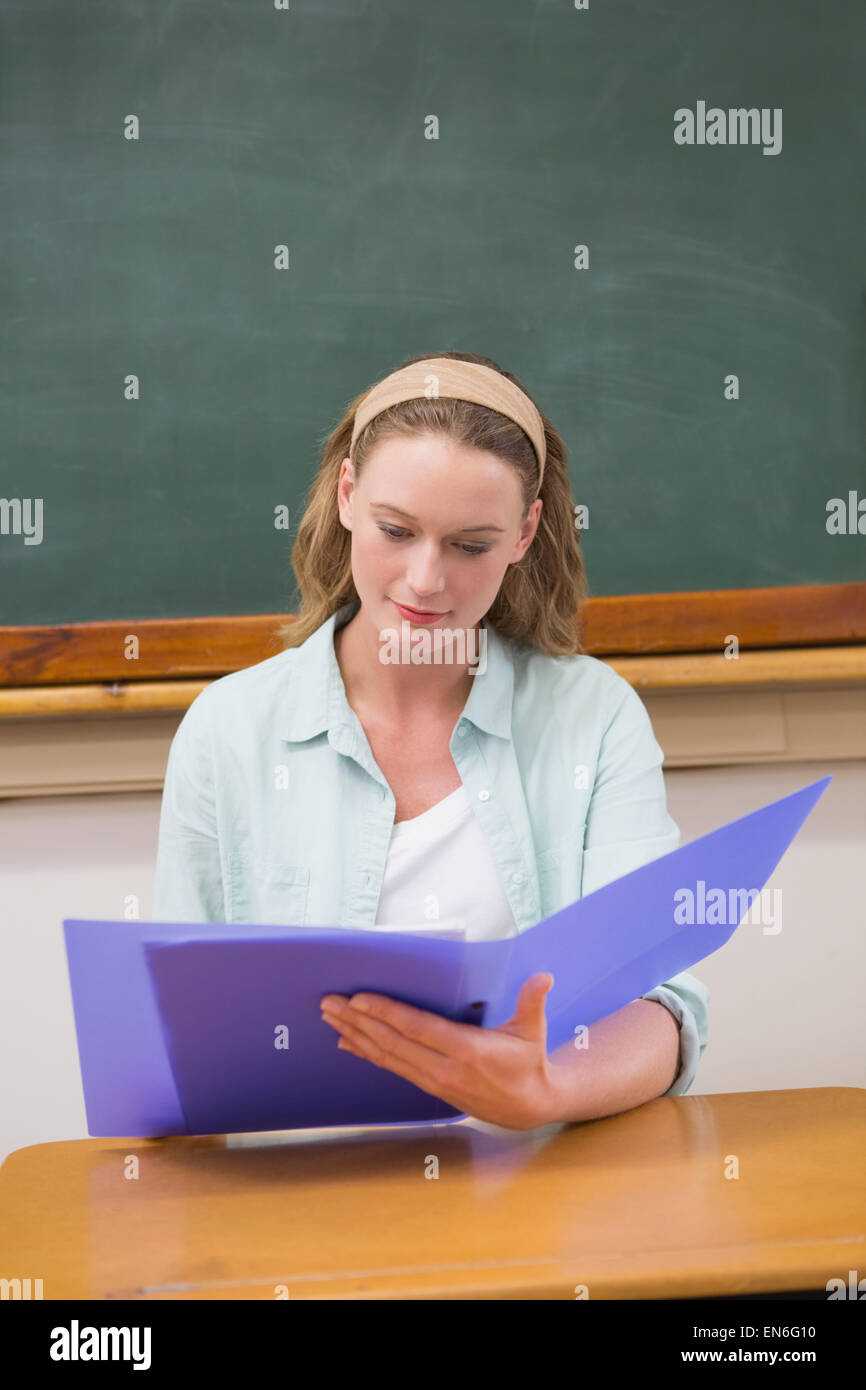 Teacher reading papers at her desk Stock Photo - Alamy