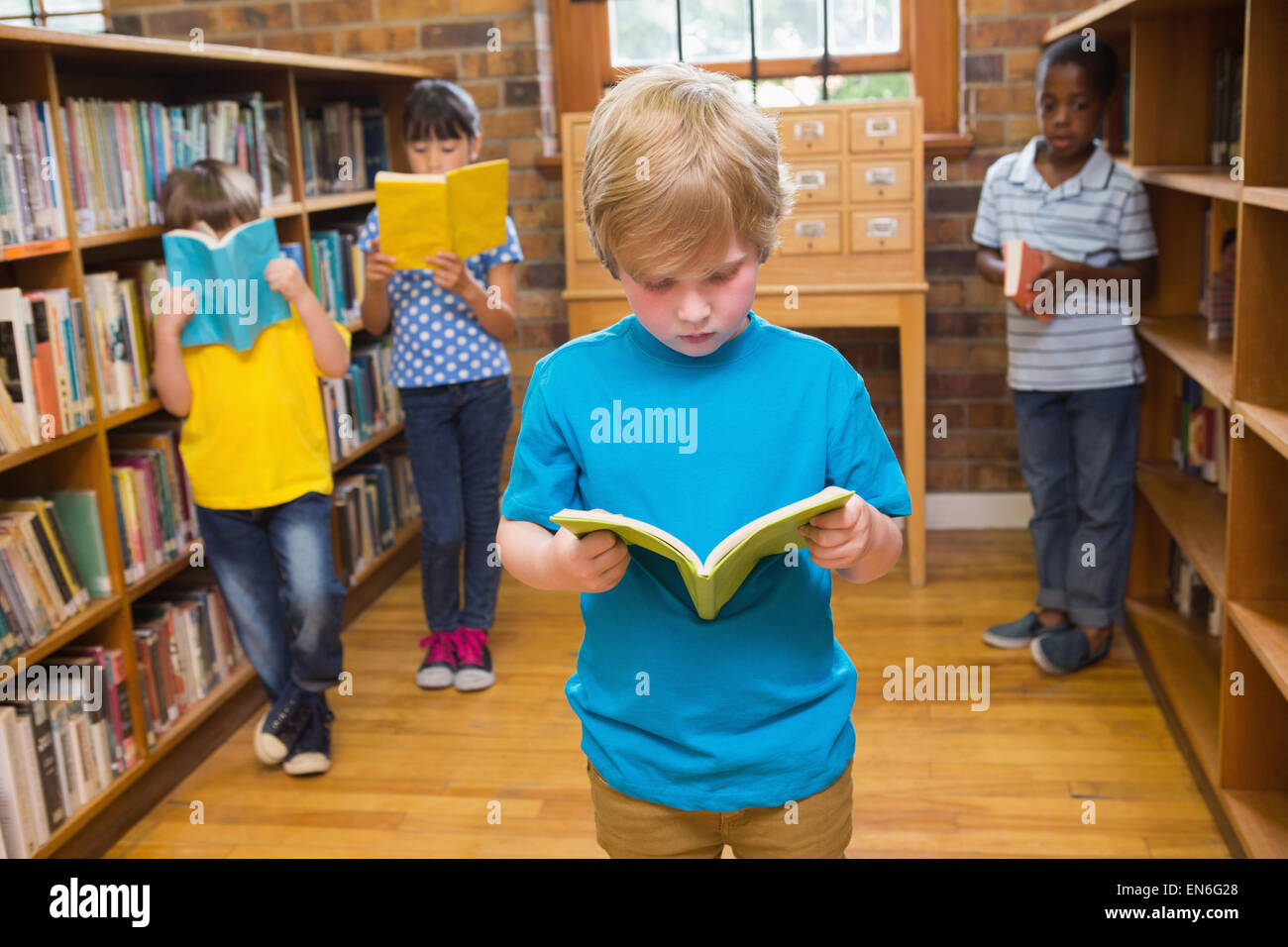 Cute pupils reading books at library Stock Photo - Alamy
