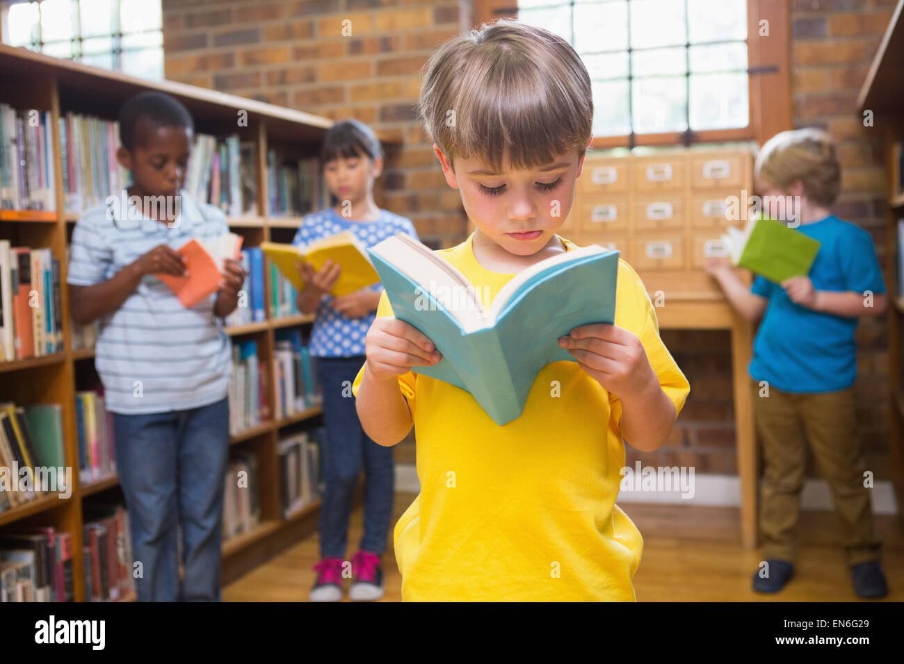 Cute pupils reading books at library Stock Photo - Alamy