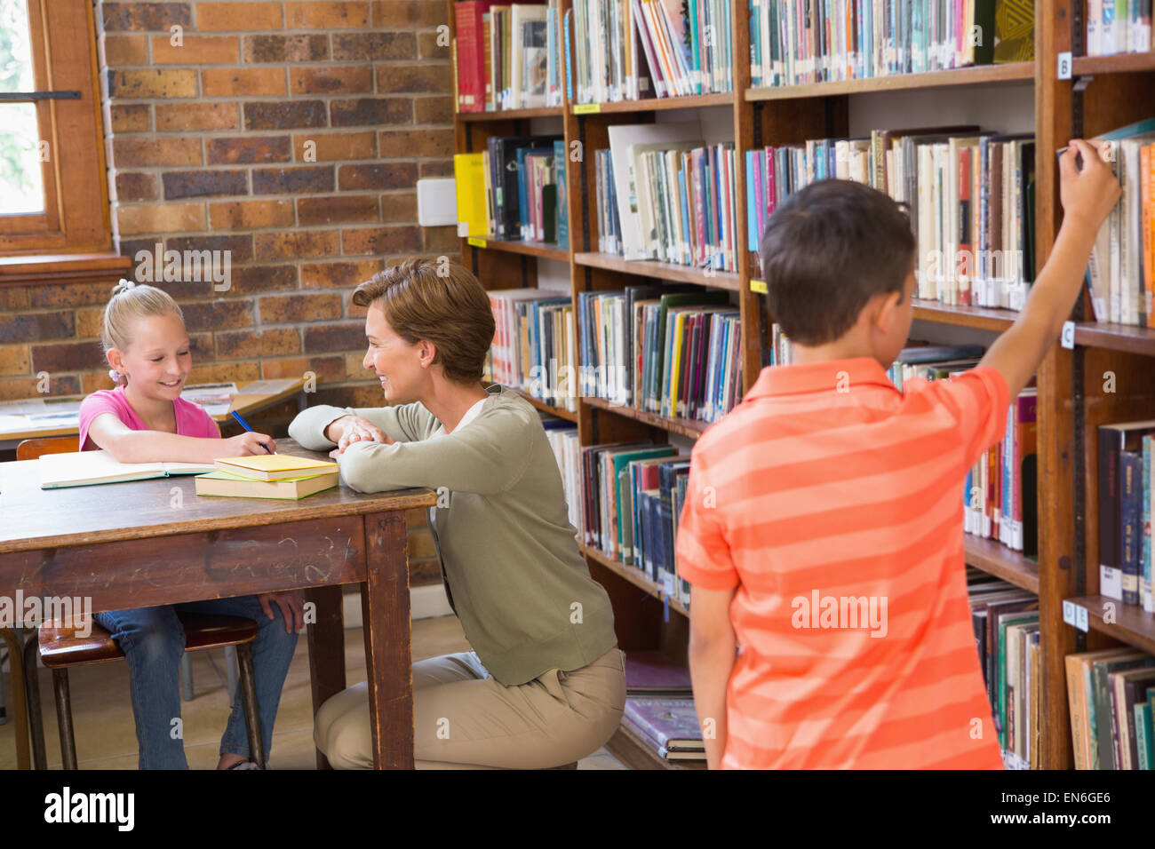 Teacher helping pupil in library Stock Photo - Alamy