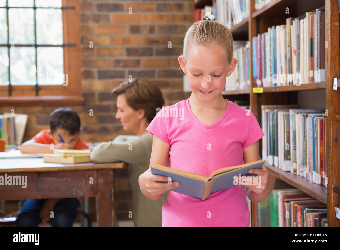 Cute pupil reading in library Stock Photo - Alamy