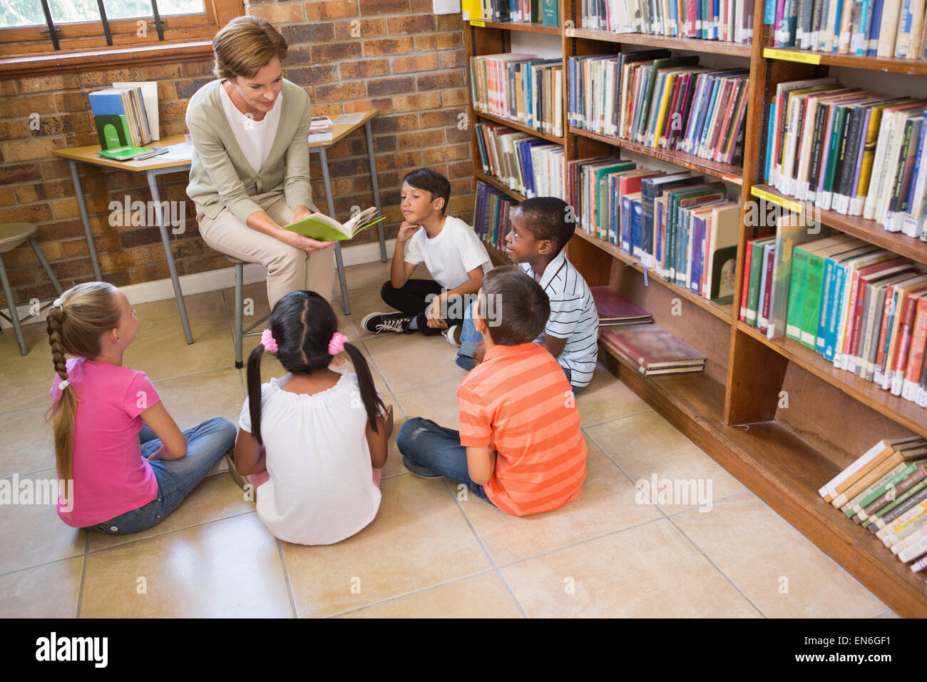 Cute pupils and teacher having class in library Stock Photo - Alamy