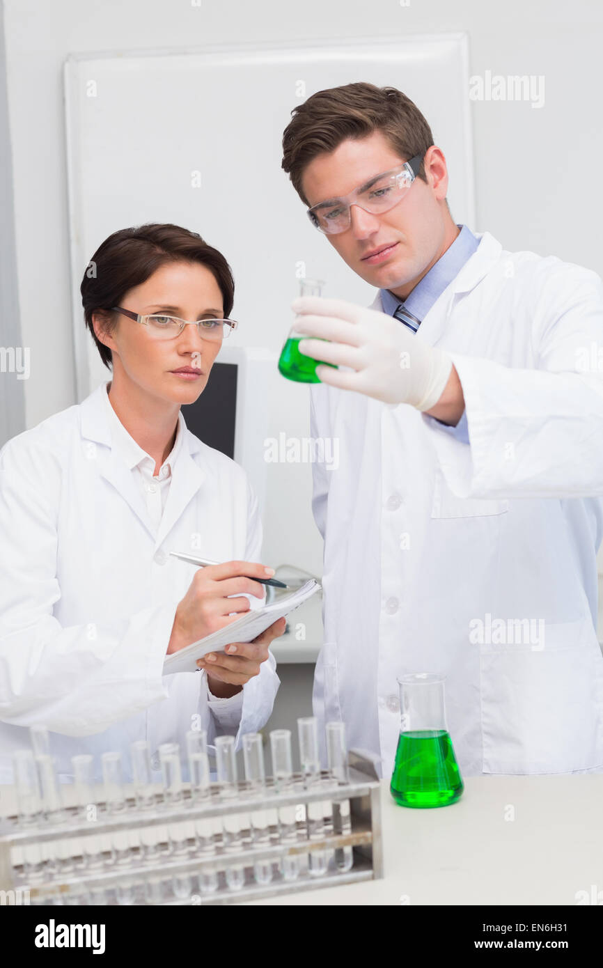 Scientists examining attentively beaker with green fluid Stock Photo ...