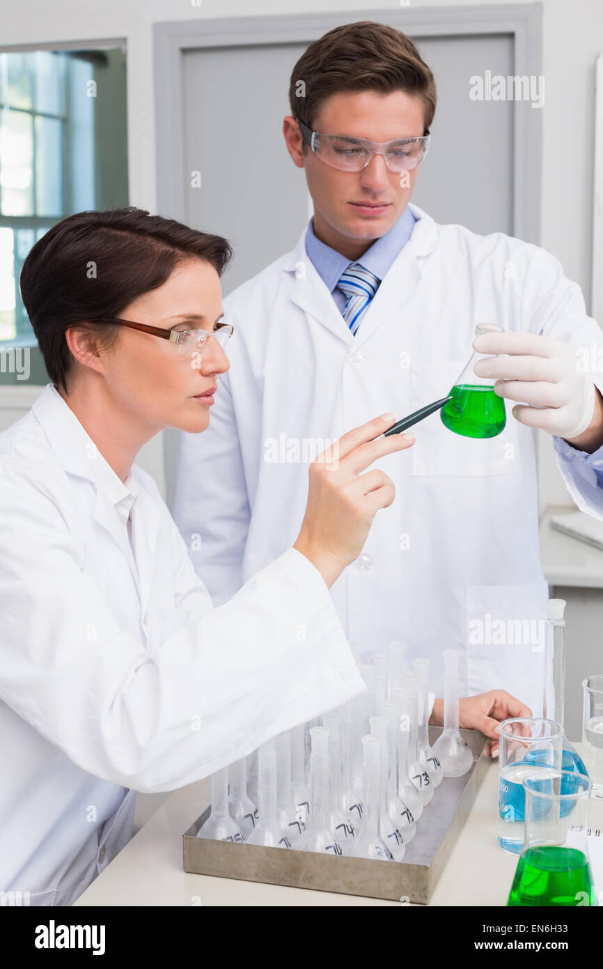 Scientists examining attentively beaker with green fluid Stock Photo ...
