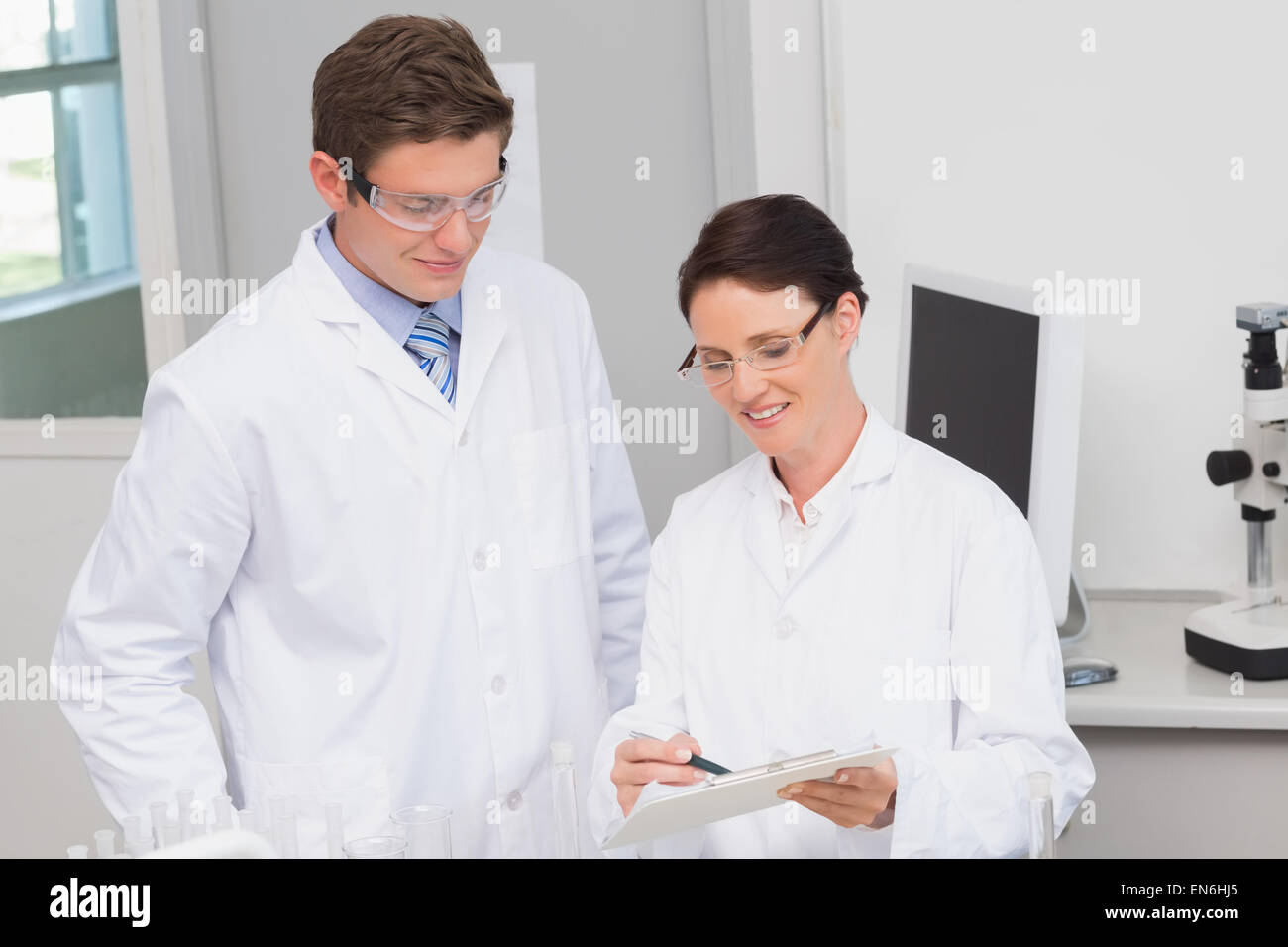 Smiling scientists looking at clipboard Stock Photo - Alamy