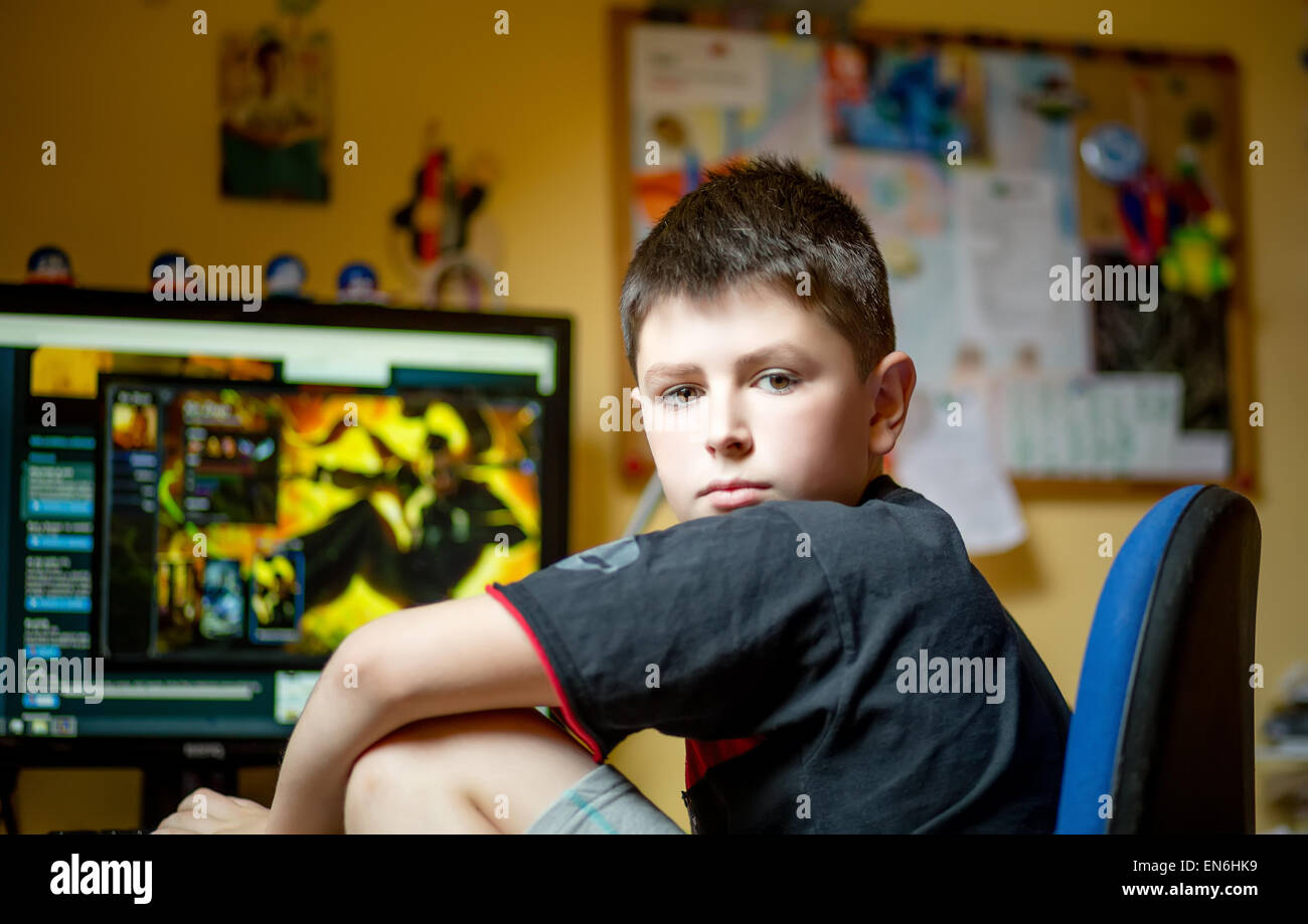 Teenager using computer at home with headphones, play game in his child ...