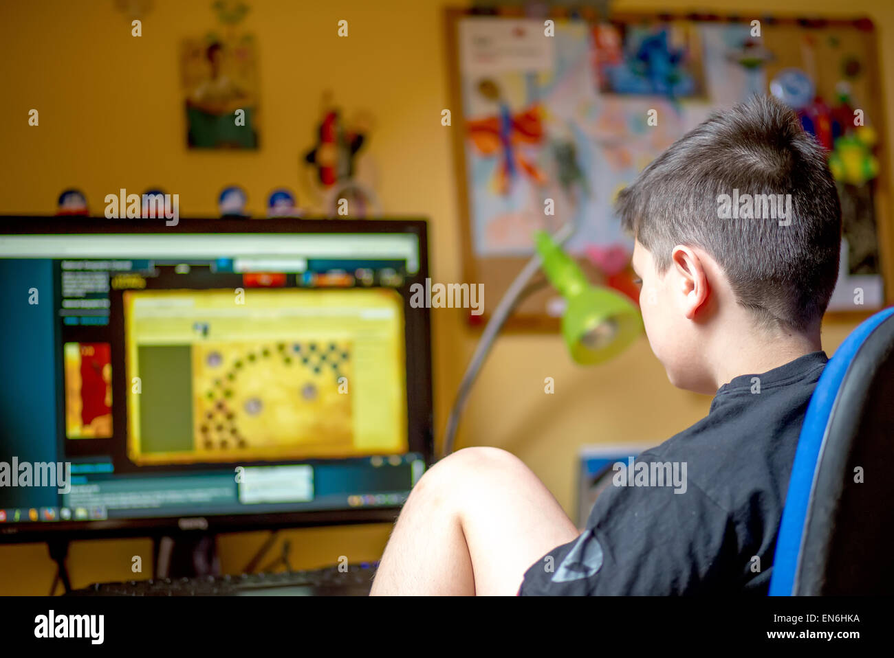 Teenager using computer at home with headphones, play game in his child ...