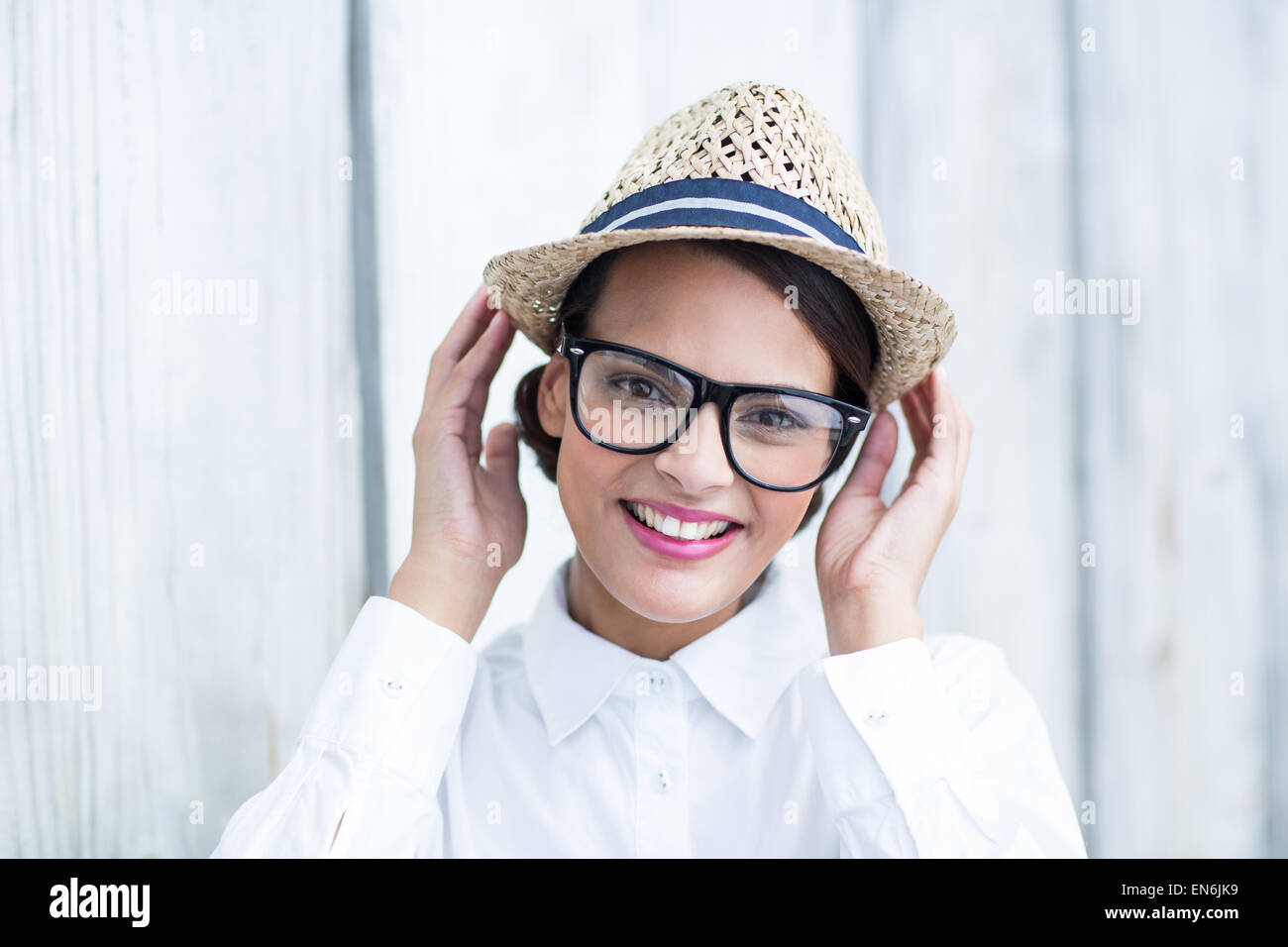 Pretty brunette looking at camera with hands on hat Stock Photo - Alamy