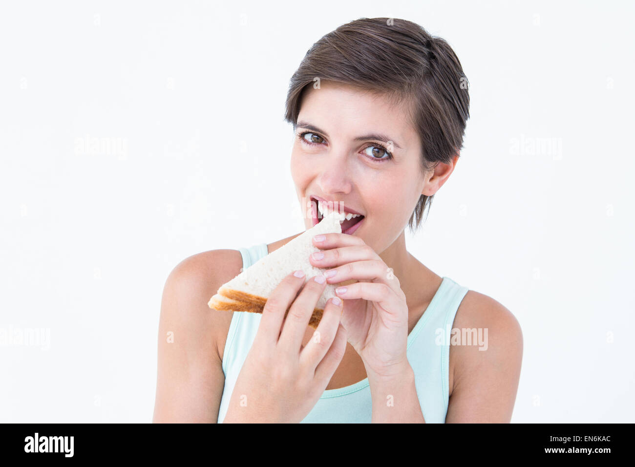 Happy brunette eating sandwich Stock Photo - Alamy