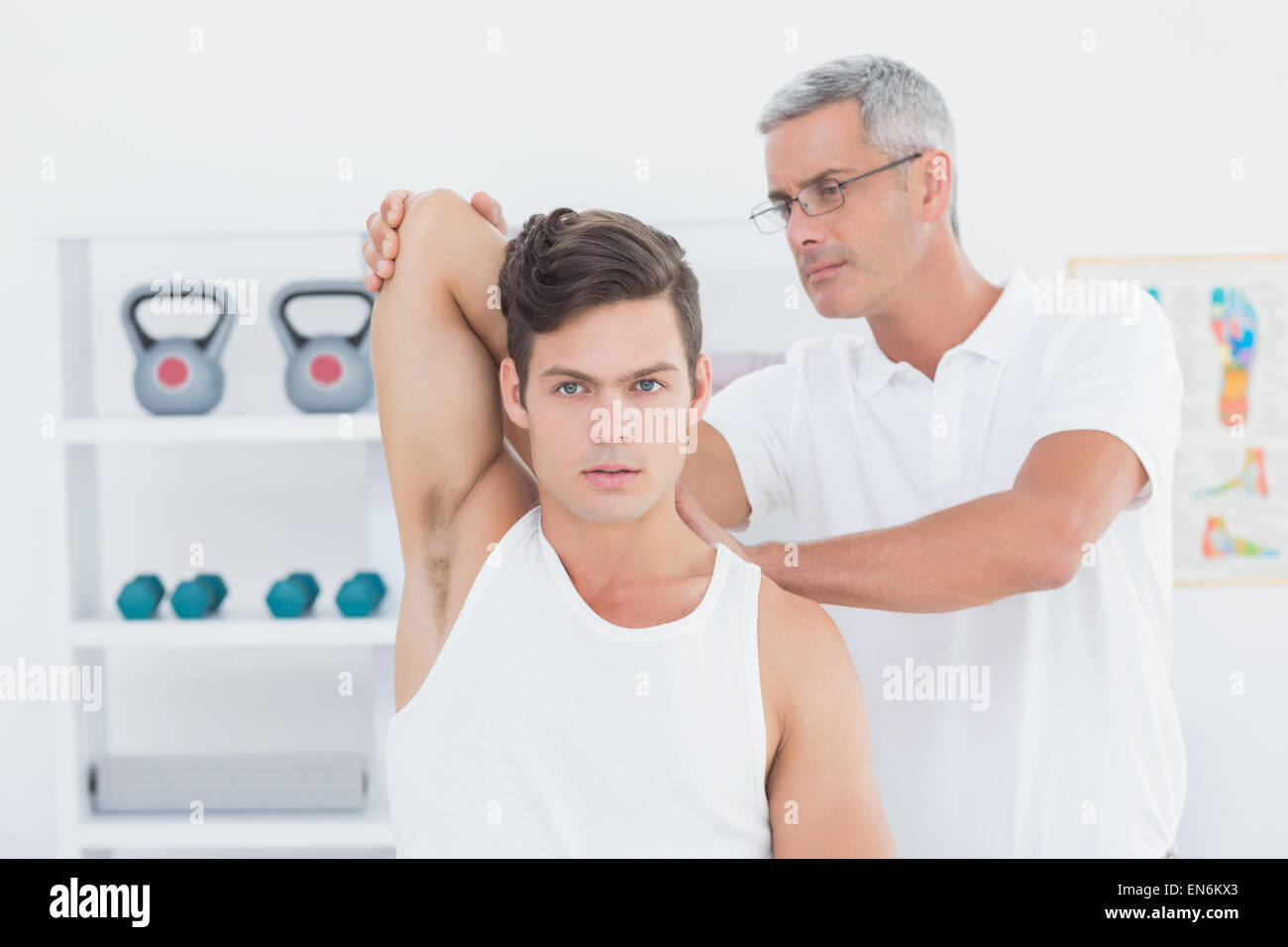 Doctor stretching a young man arm Stock Photo - Alamy