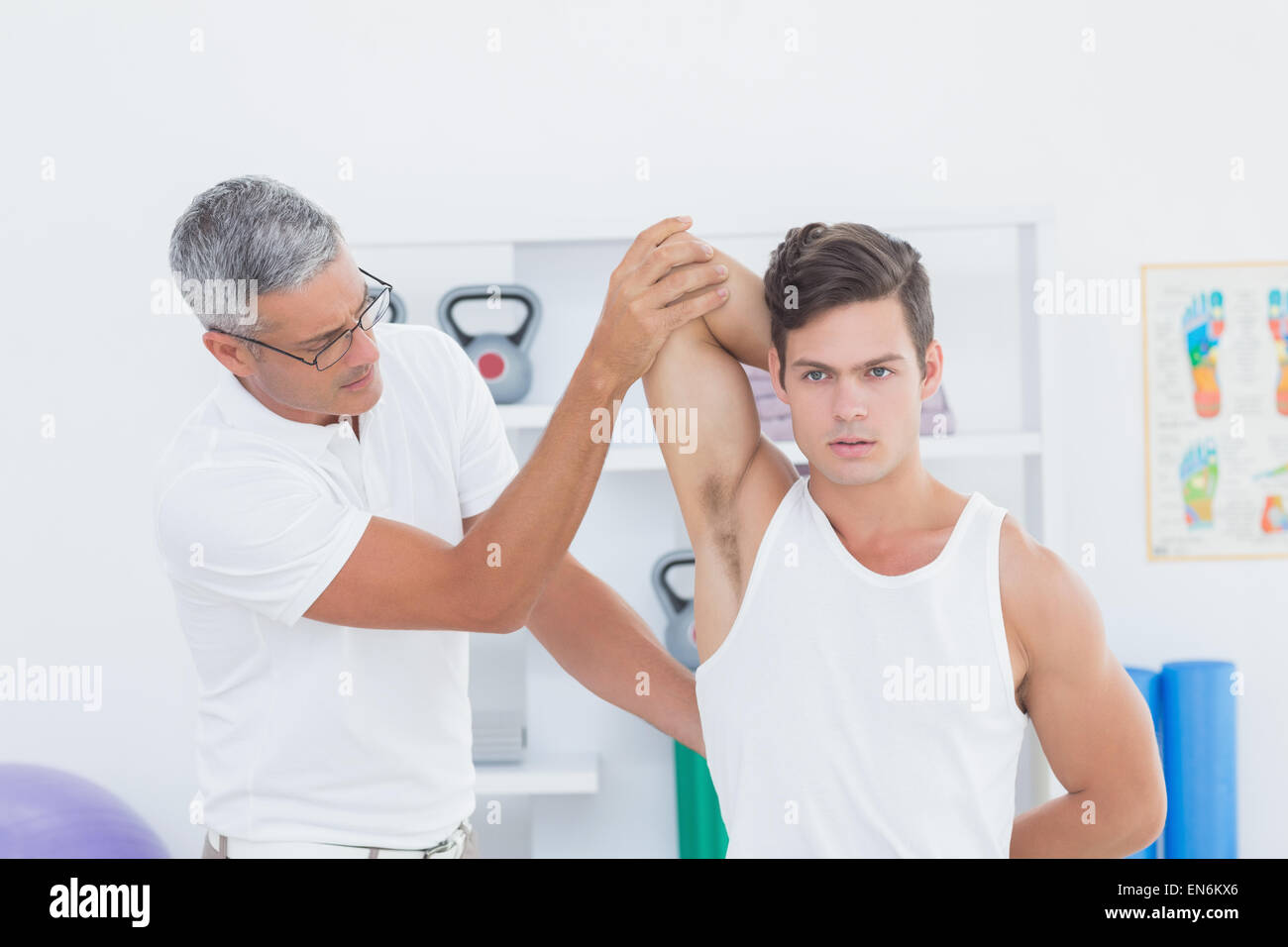 Doctor stretching a young man arm Stock Photo - Alamy