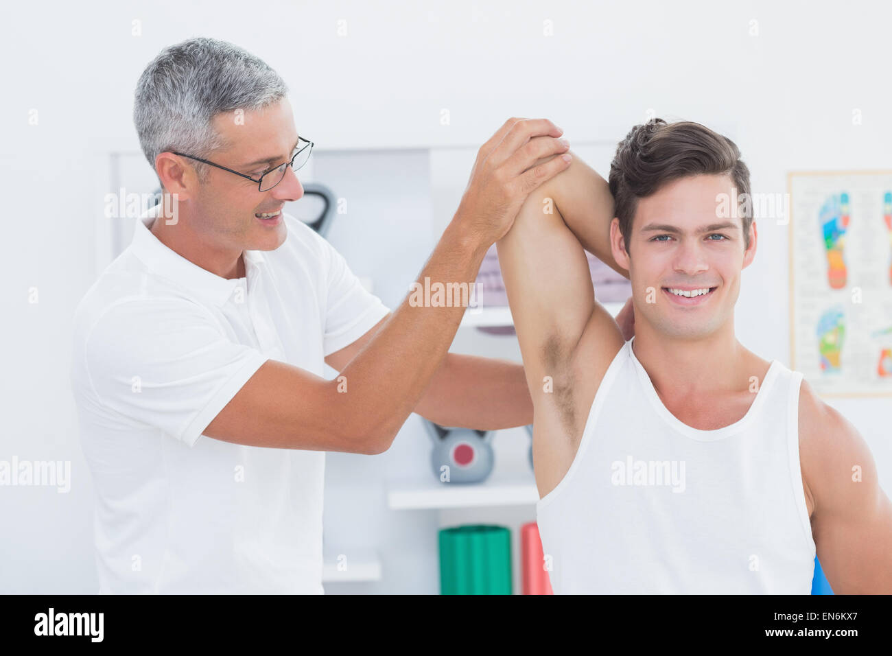 Doctor stretching a young man arm Stock Photo - Alamy