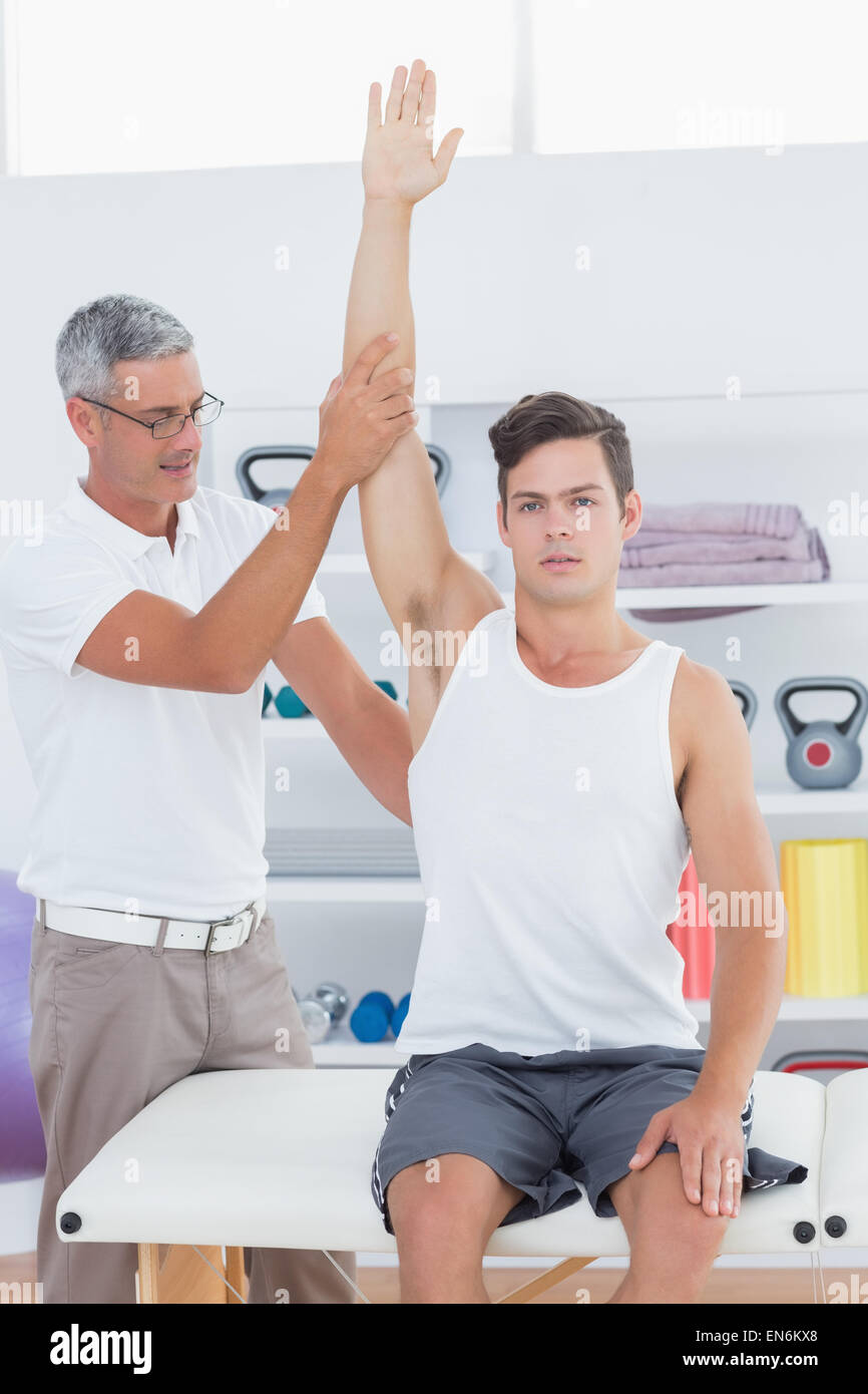 Doctor raising a young man arm Stock Photo - Alamy