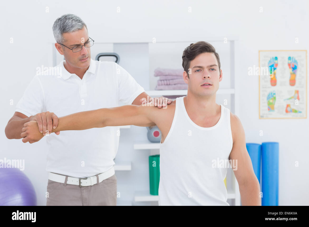 Doctor stretching a young man arm Stock Photo - Alamy