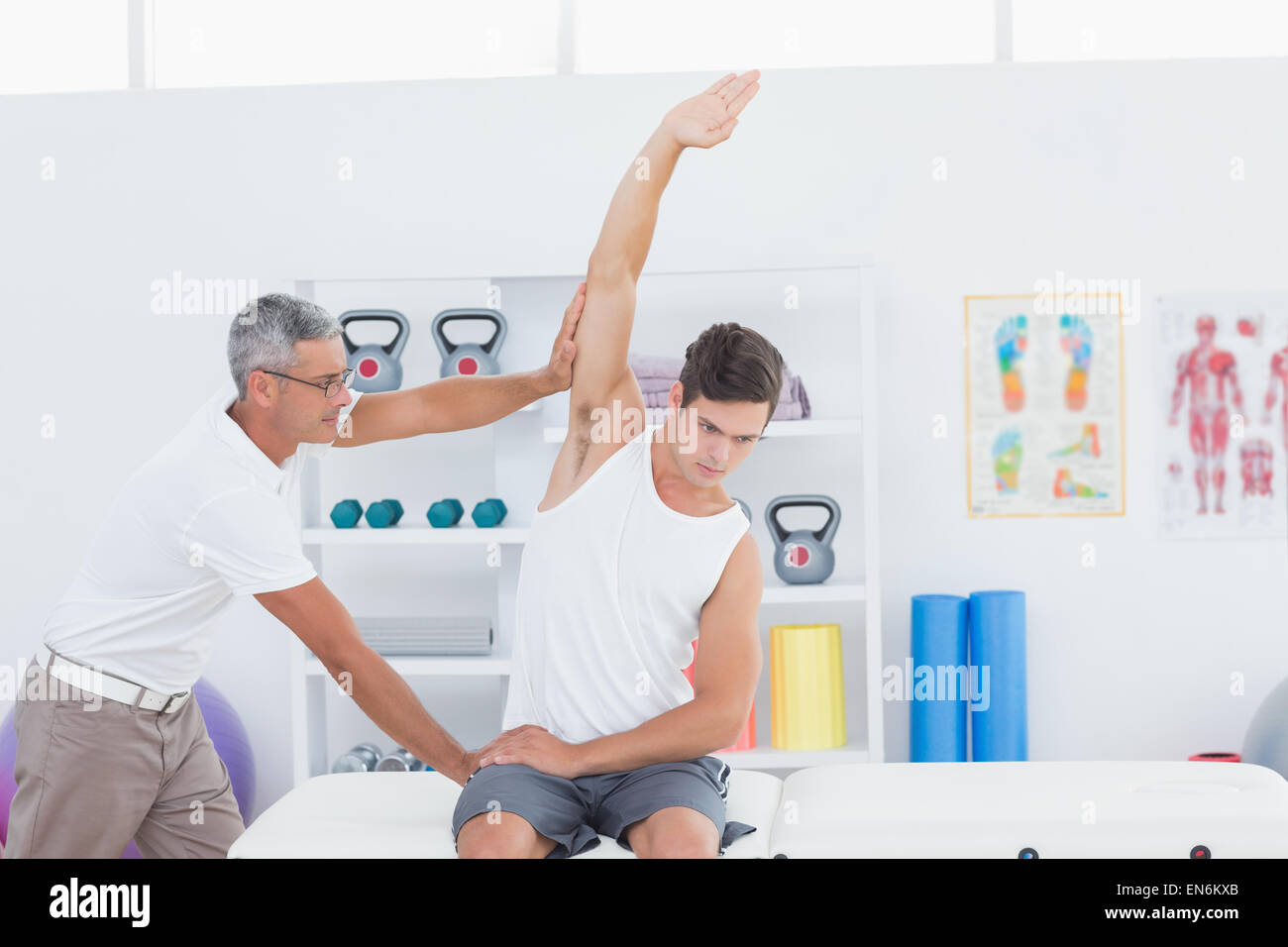 Doctor stretching a young man arm Stock Photo - Alamy