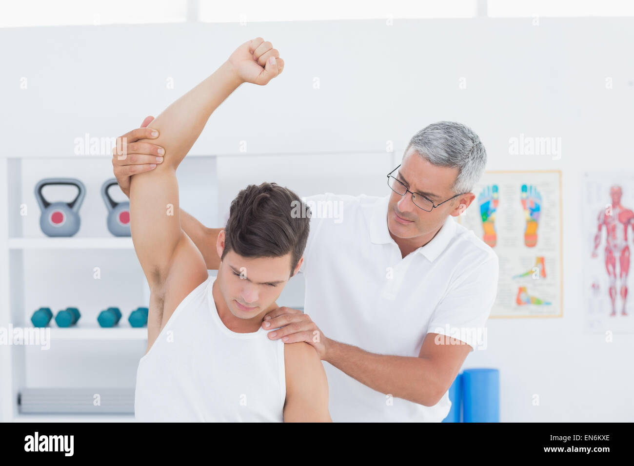 Doctor stretching a young man arm Stock Photo - Alamy