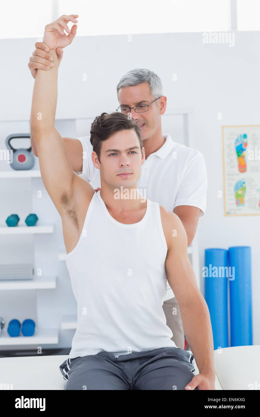 Doctor stretching a young man arm Stock Photo - Alamy