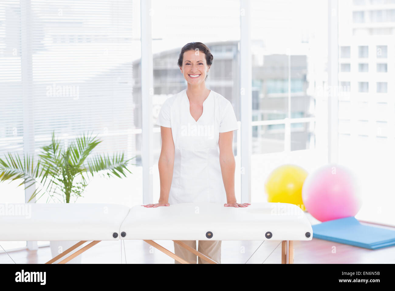 Smiling doctor looking at camera standing behind massage table Stock ...