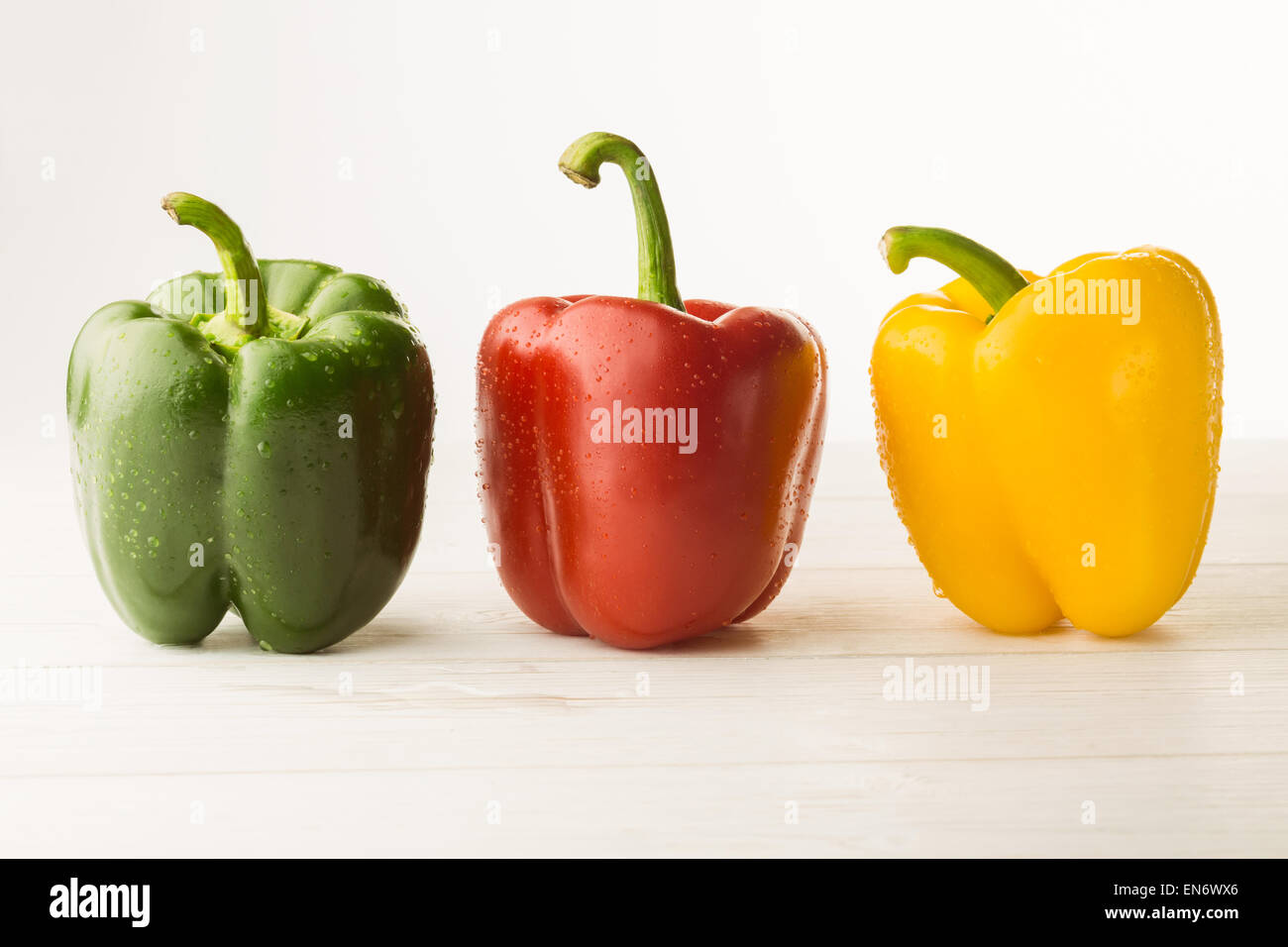 Three peppers on chopping board Stock Photo - Alamy