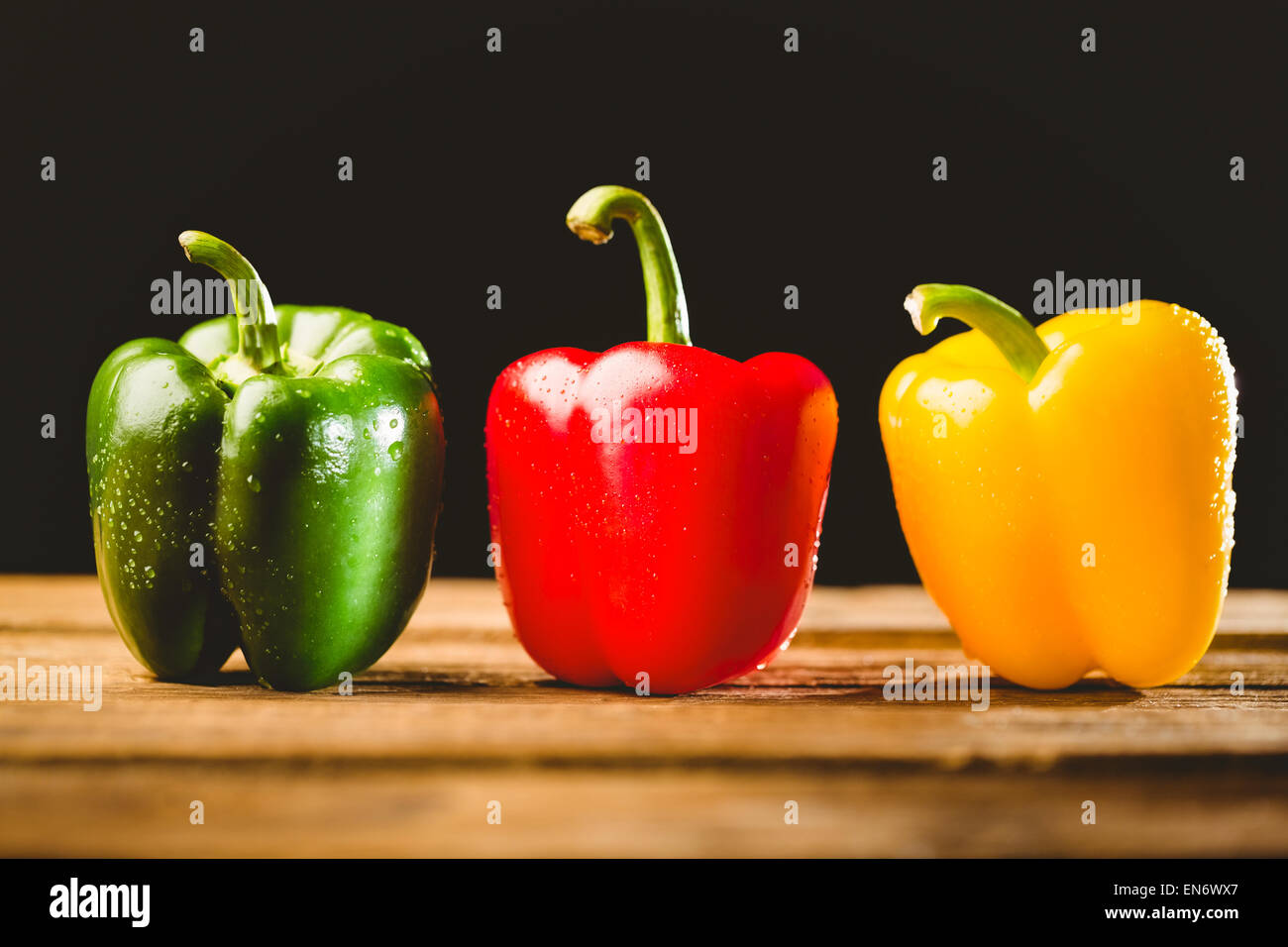 Three peppers on chopping board Stock Photo - Alamy