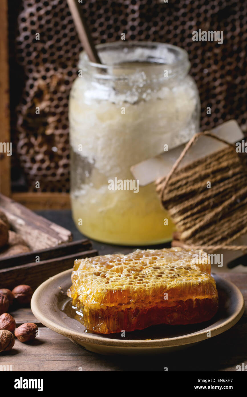 Fresh honeycomb with jar of old honey and mix of nuts over old wooden ...