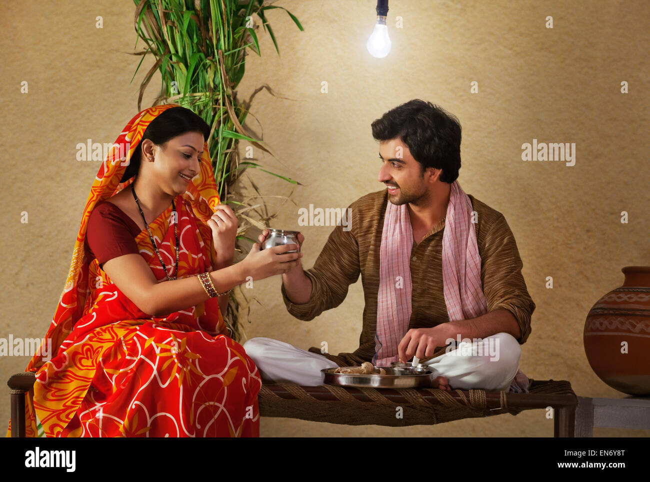 Rural woman offering water to husband Stock Photo - Alamy