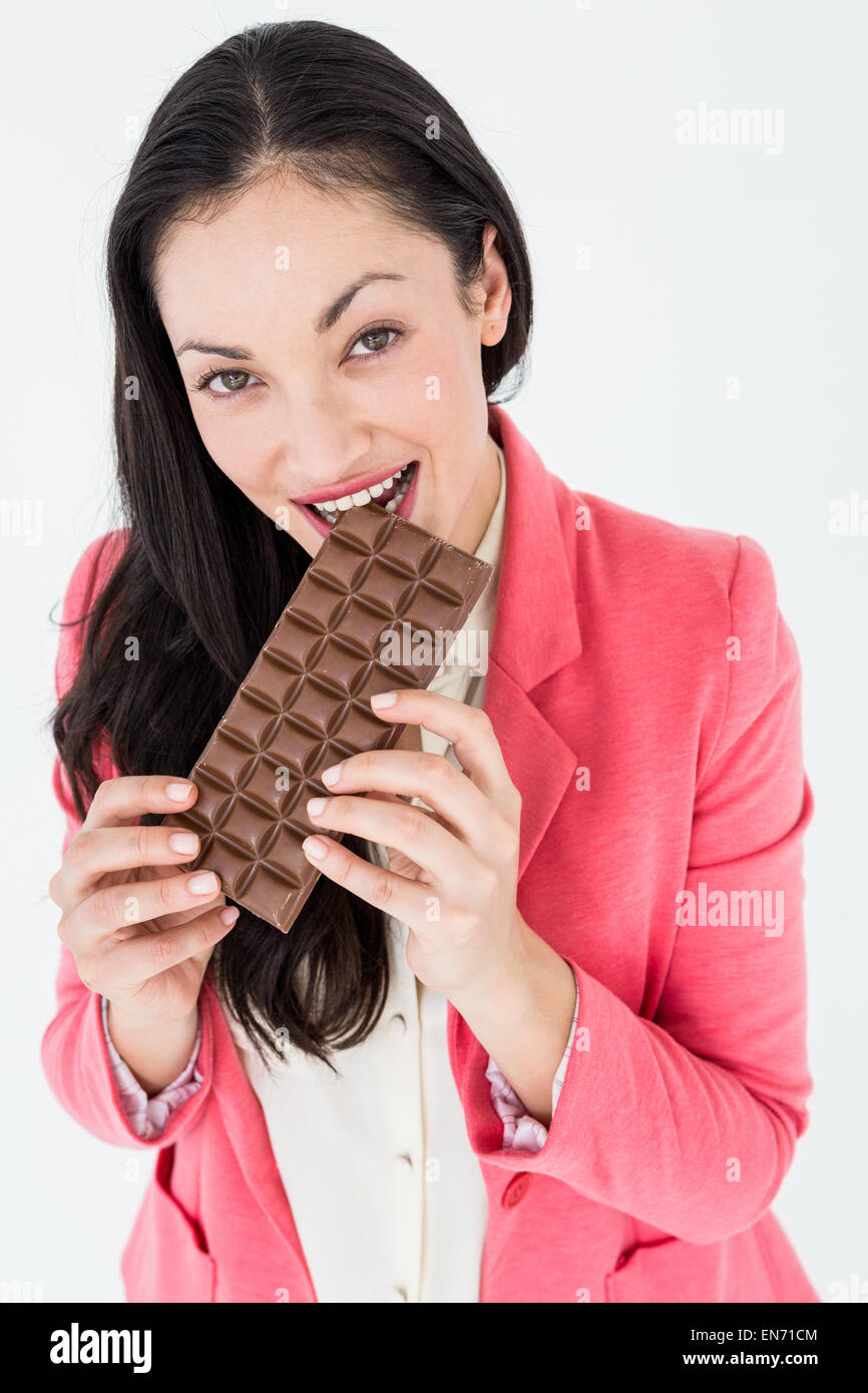 Smiling brunette biting bar of chocolate Stock Photo - Alamy