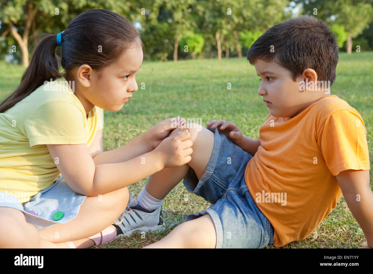 Girl putting band-aid on brothers leg Stock Photo - Alamy