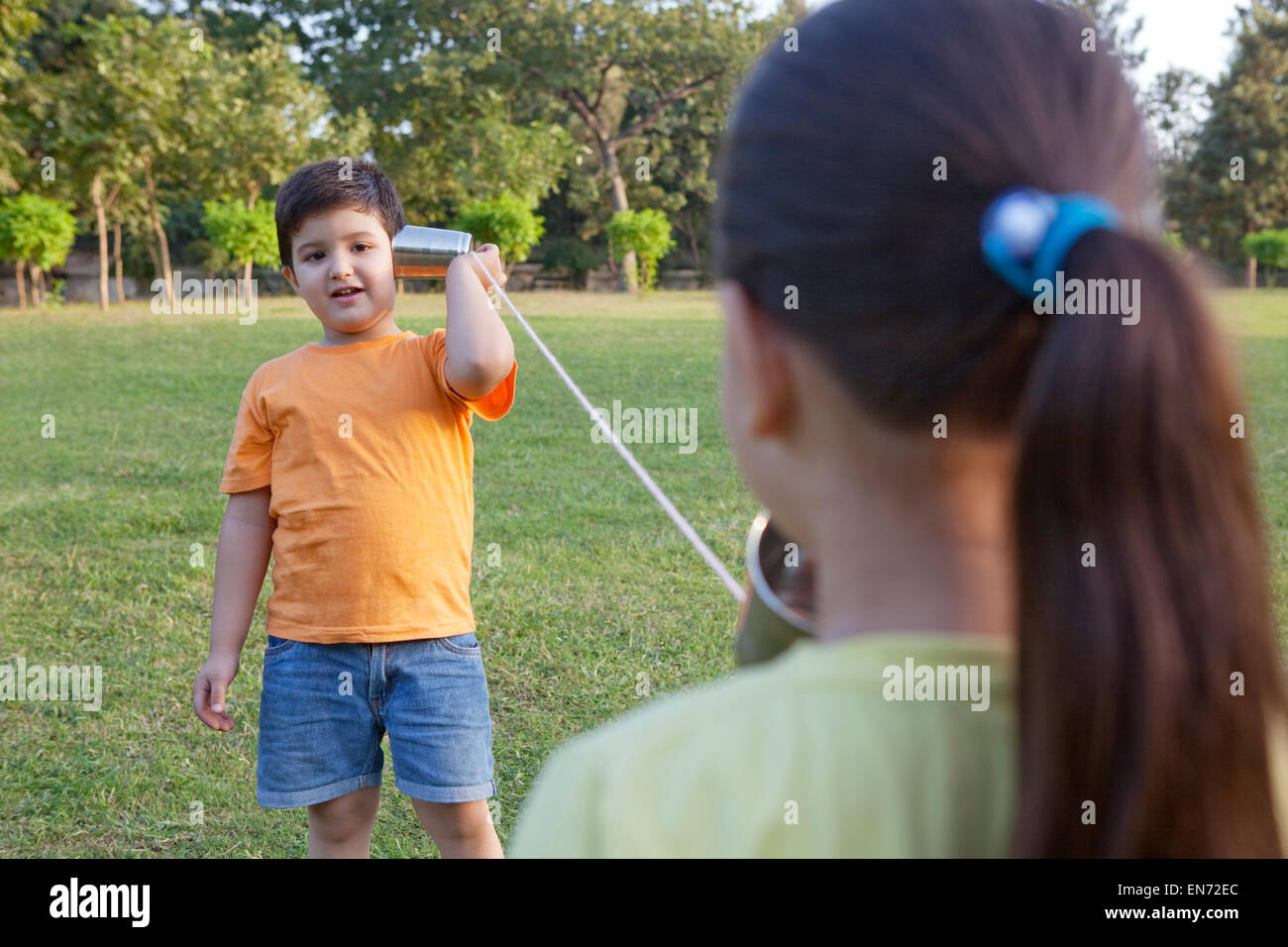 Brother and sister talking through tin cans Stock Photo - Alamy