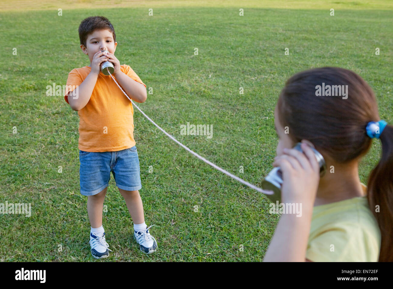 Brother and sister talking through tin cans Stock Photo - Alamy