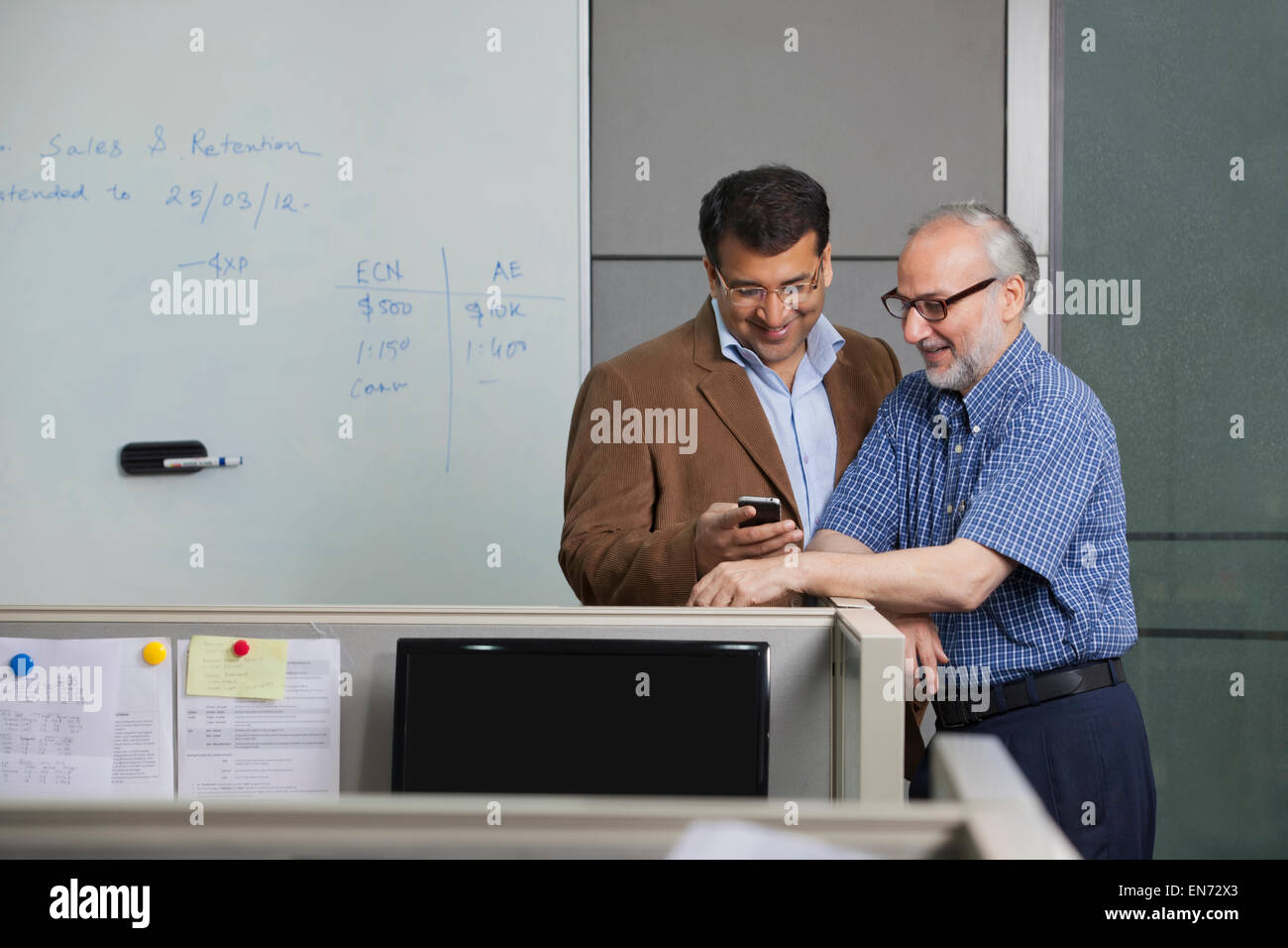 Two male executives looking at sms on mobile phone Stock Photo - Alamy