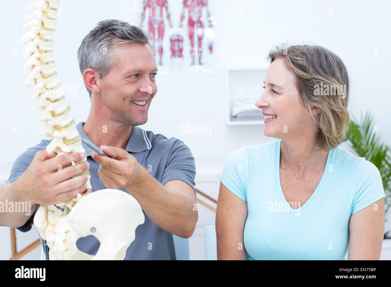 Physiotherapist showing spine model to his patient Stock Photo - Alamy