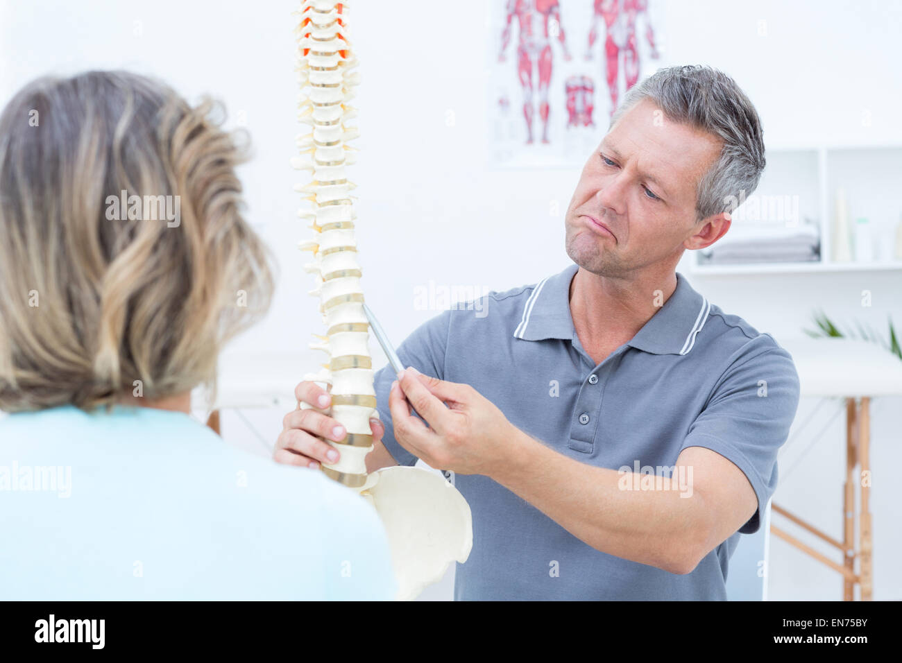 Physiotherapist showing spine model to his patient Stock Photo - Alamy