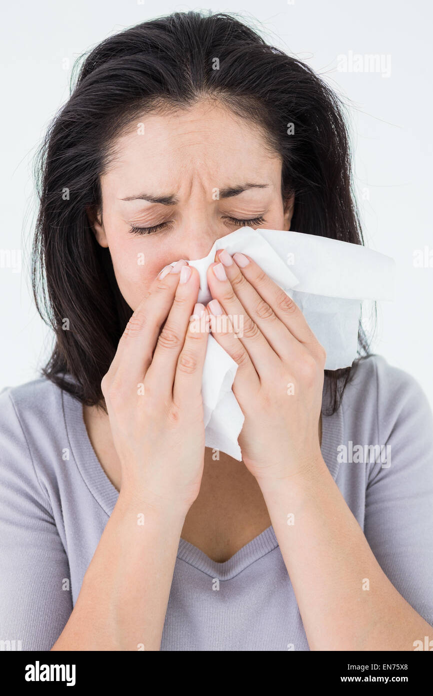 Sick brunette blowing her nose Stock Photo - Alamy