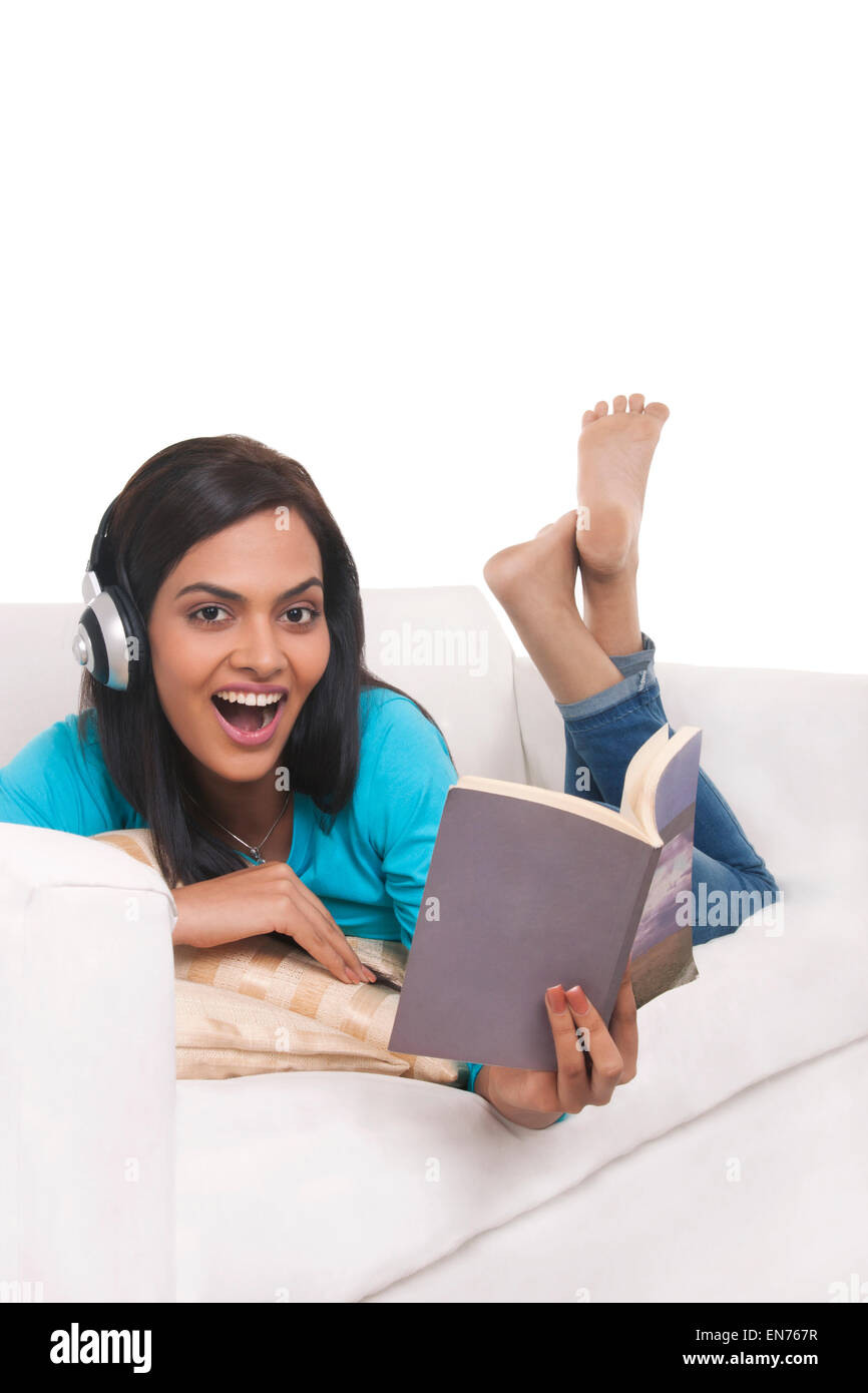 Young woman listening to music while reading Stock Photo - Alamy