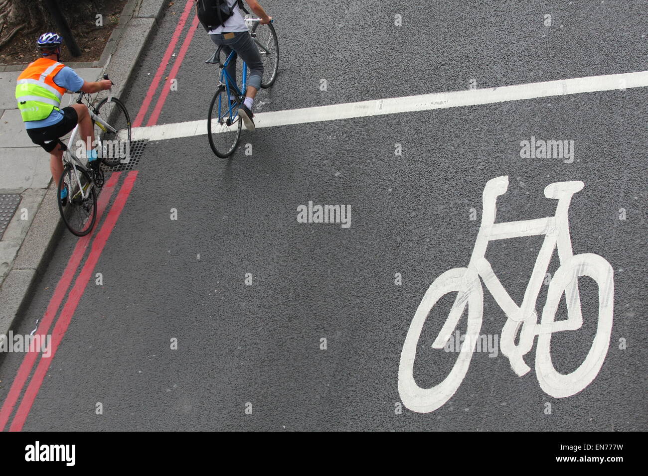 Two cyclists riding through a cycling zone marked in the street in ...