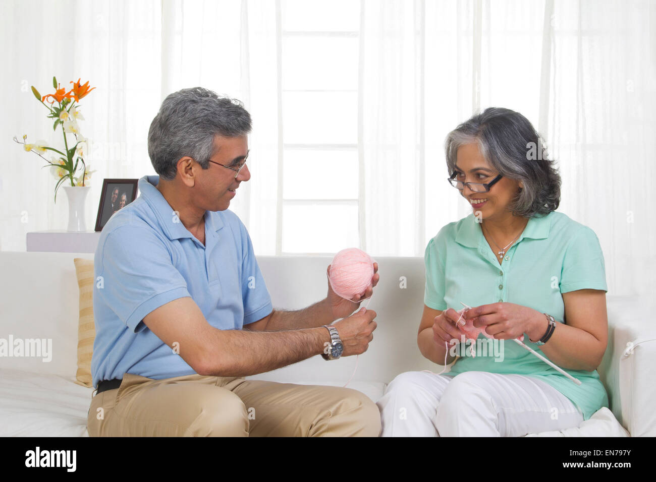 Husband helping while his wife is knitting Stock Photo - Alamy
