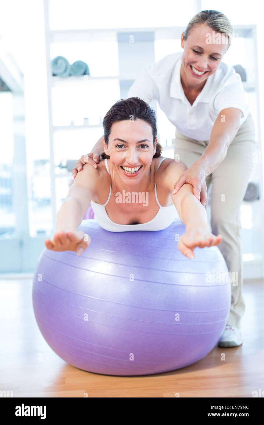Trainer helping woman on exercise ball Stock Photo - Alamy