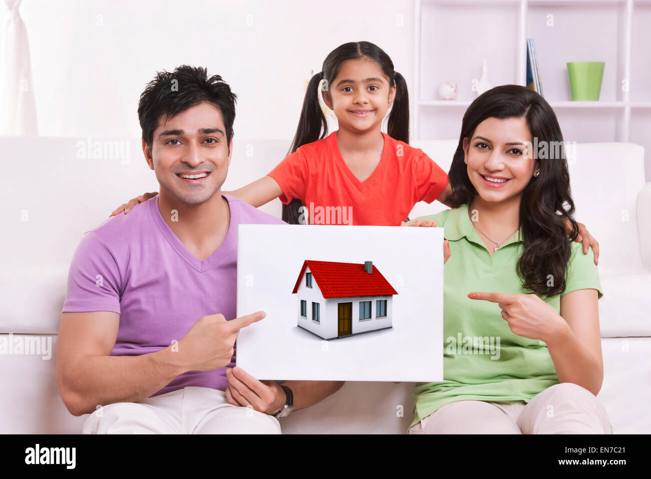 Portrait of family pointing to picture of house Stock Photo - Alamy