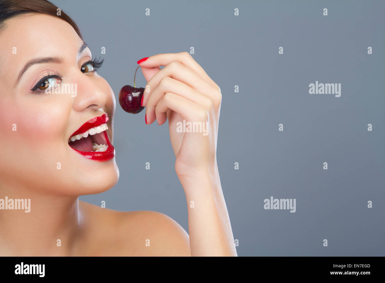 Portrait of a woman about to eat a cherry Stock Photo - Alamy