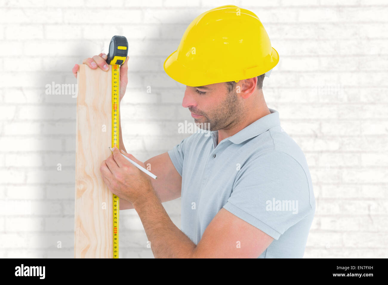 Composite image of carpenter using measure tape to mark on wooden plank ...