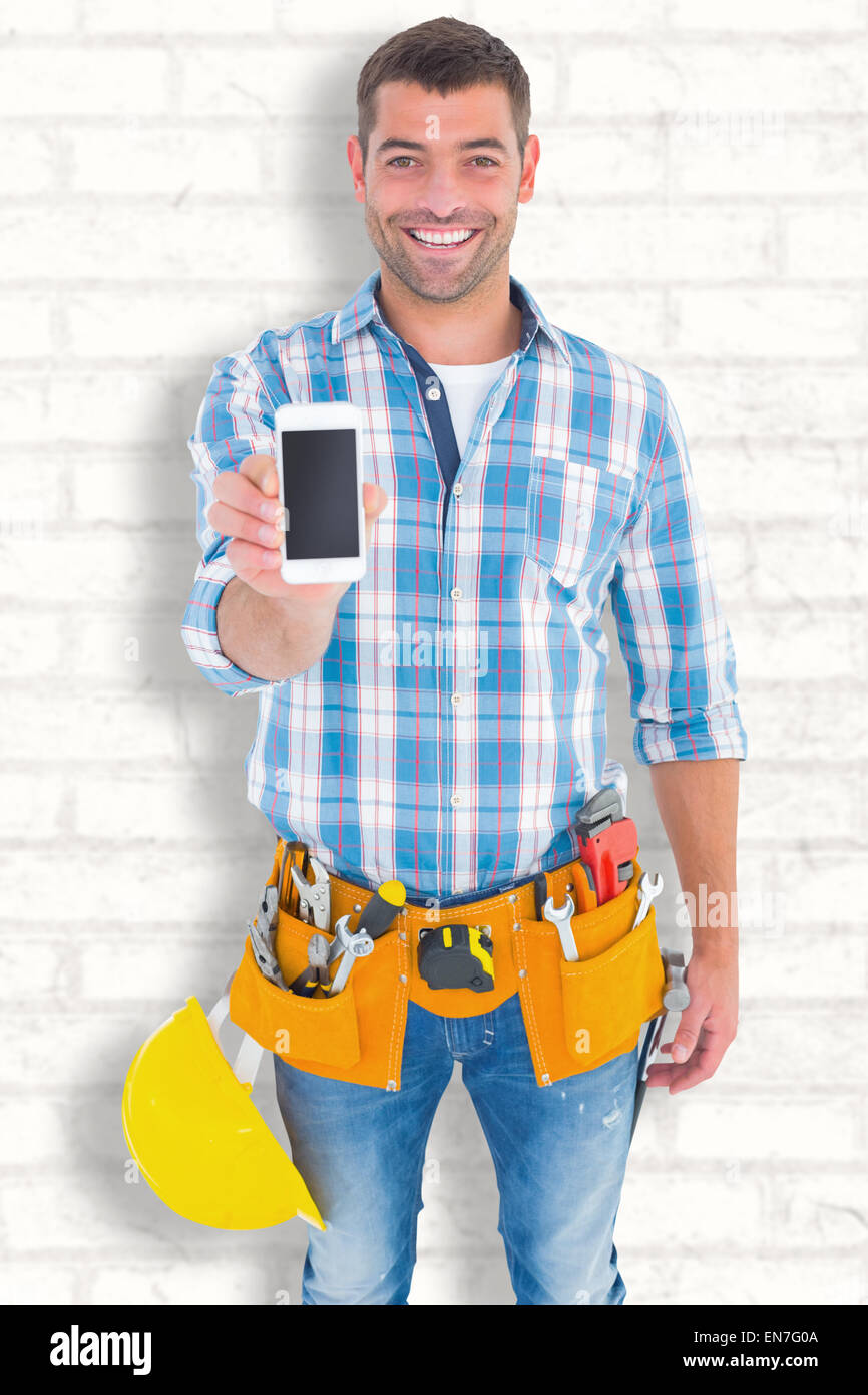 Composite image of portrait of smiling handyman showing mobile phone ...